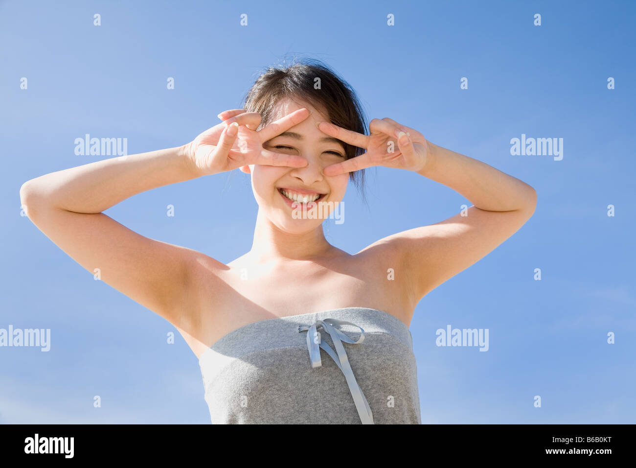 Young woman making peace sign Stock Photo - Alamy