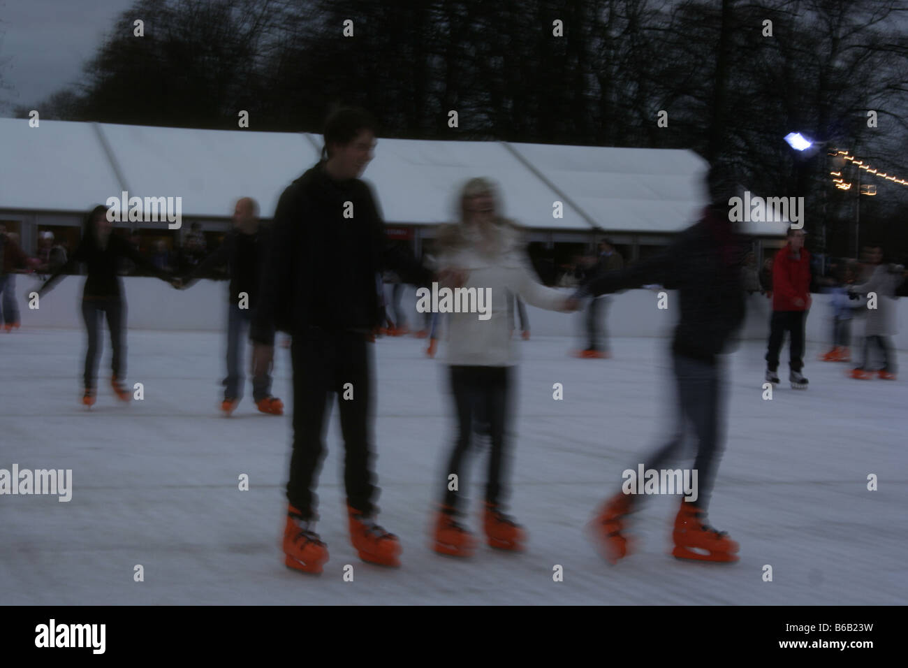 people holding hands ice skating on an outdoor rink in the early ...