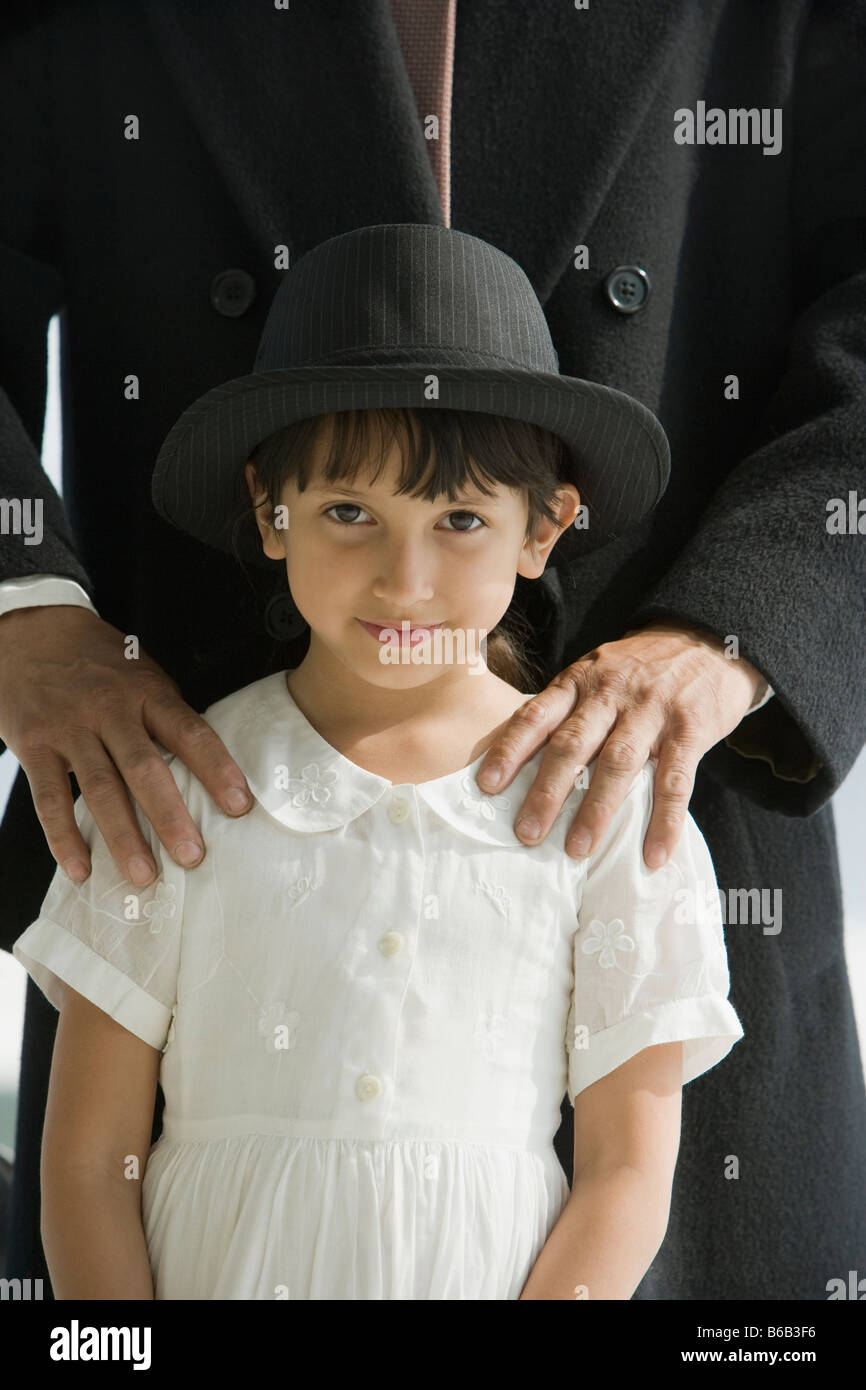 Hispanic girl standing with father wearing his hat Stock Photo - Alamy