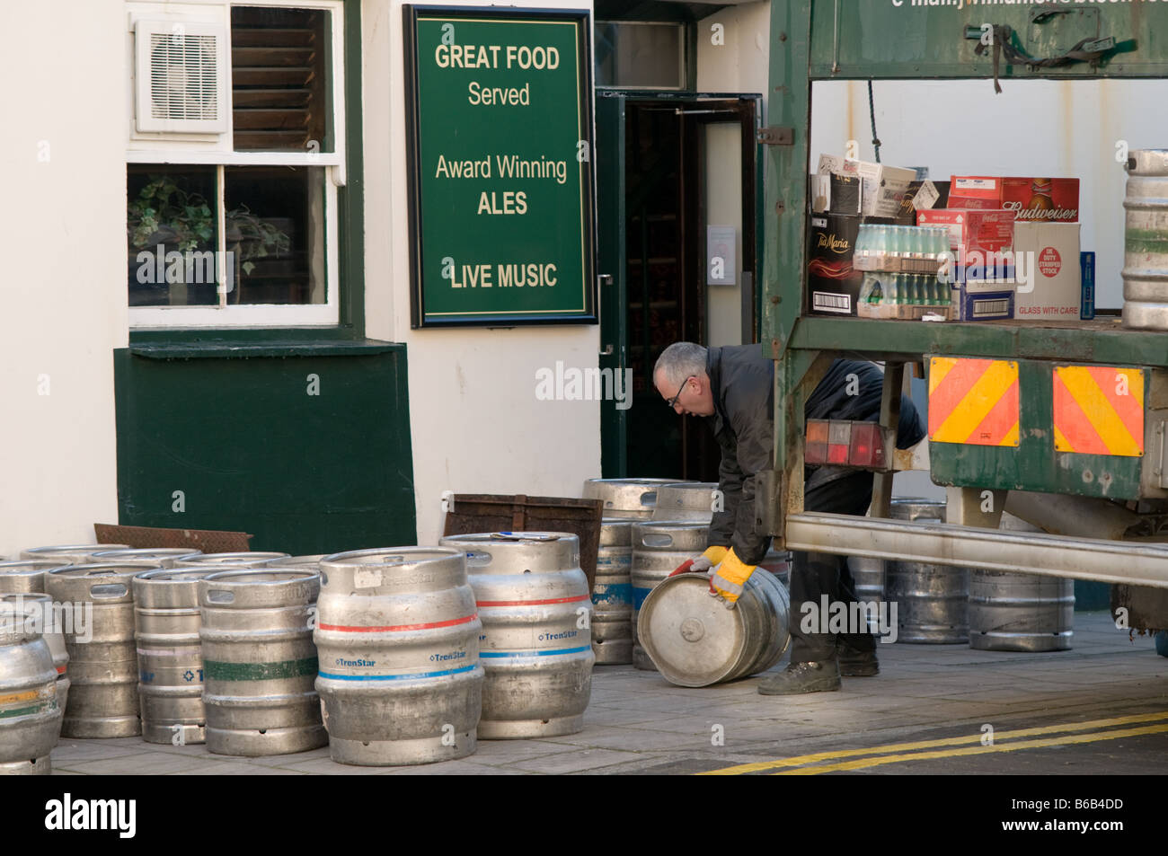 A man rolling a keg cask of beer into a pub delivering the weekly load ...