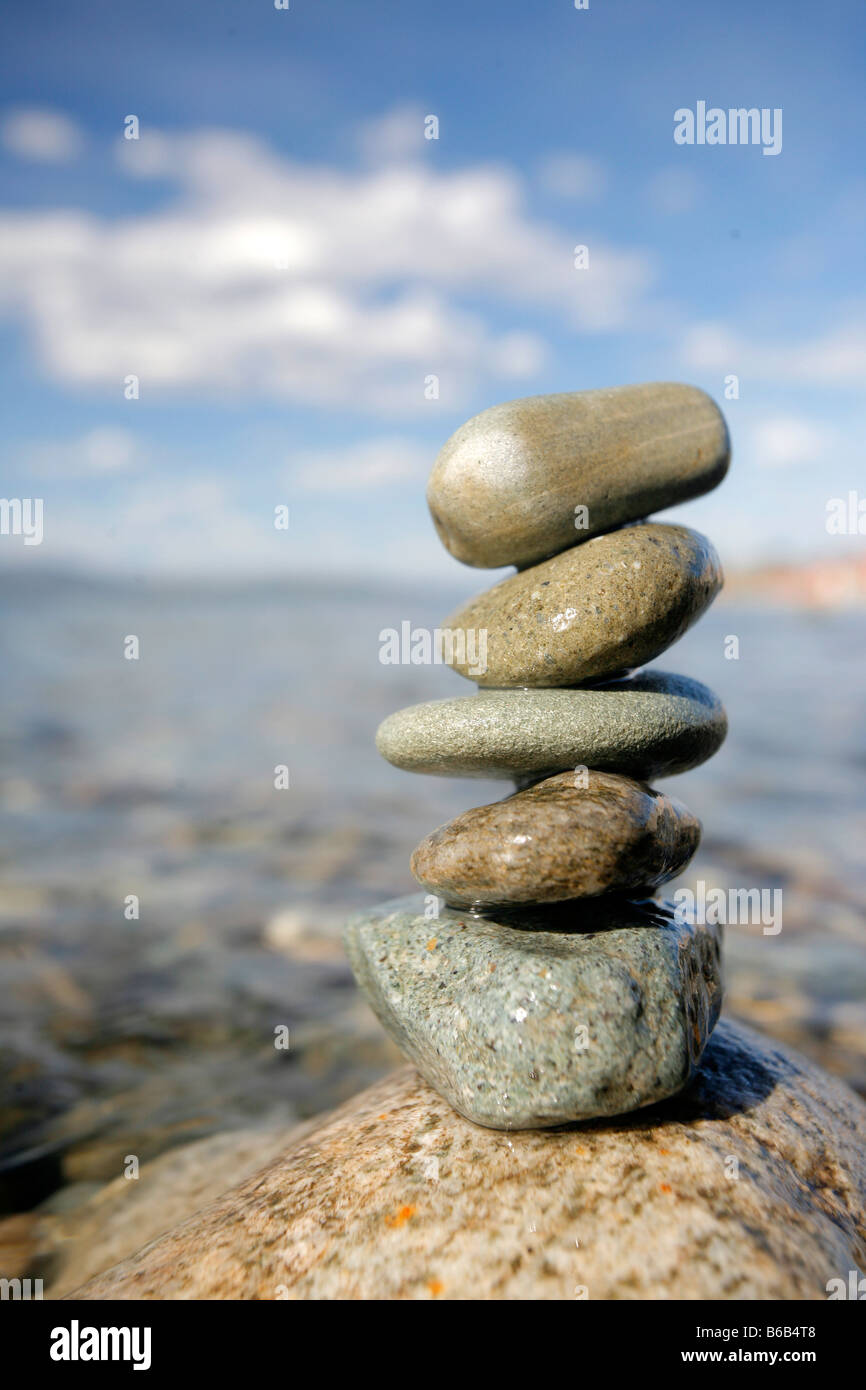 Stack of volcanic pebbles by calm water Stock Photo - Alamy
