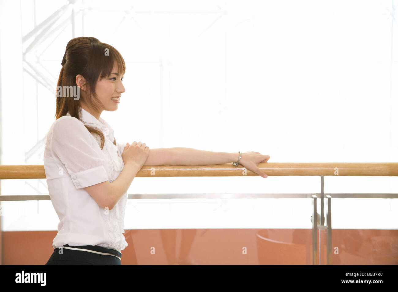 Young woman leaning against railing Stock Photo - Alamy