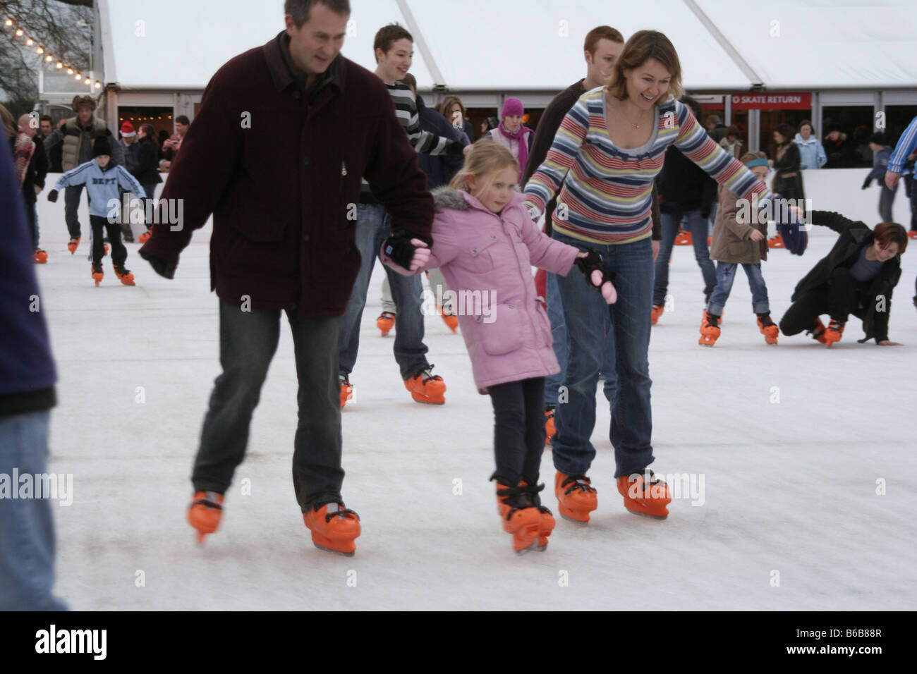 people holding hands ice skating on an outdoor rink in the early ...