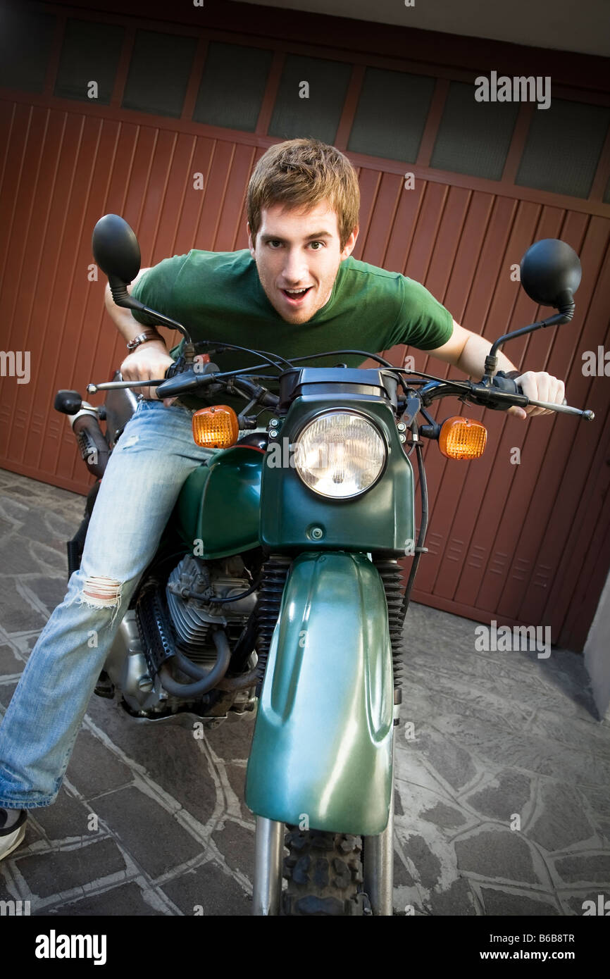 Portrait of young man sitting on motorbike Stock Photo - Alamy