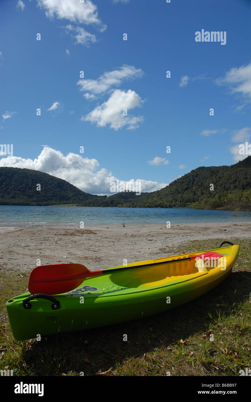Brightly coloured kayak in front of lake in New Zealand with blue sky ...