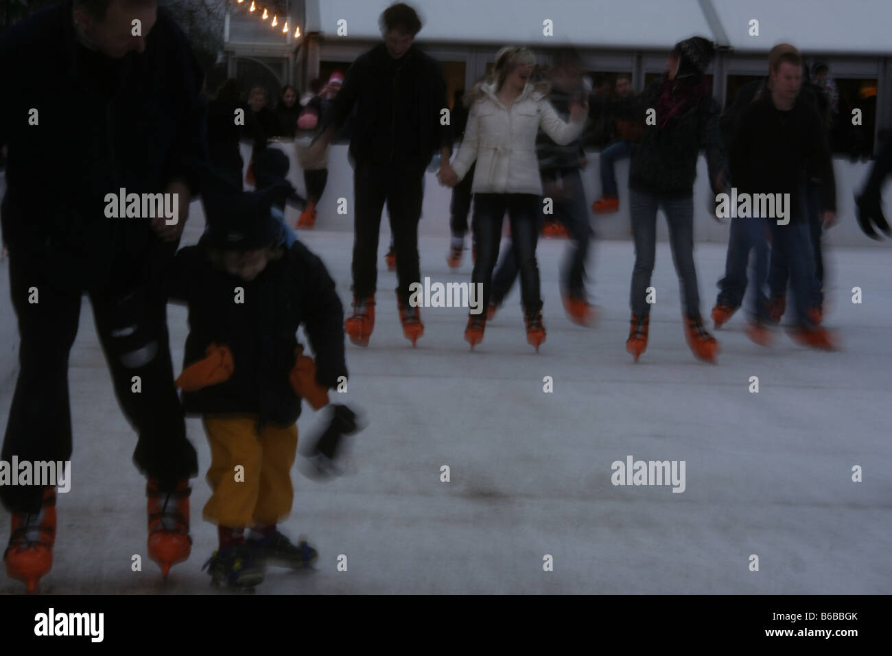 people holding hands ice skating on an outdoor rink in the early ...