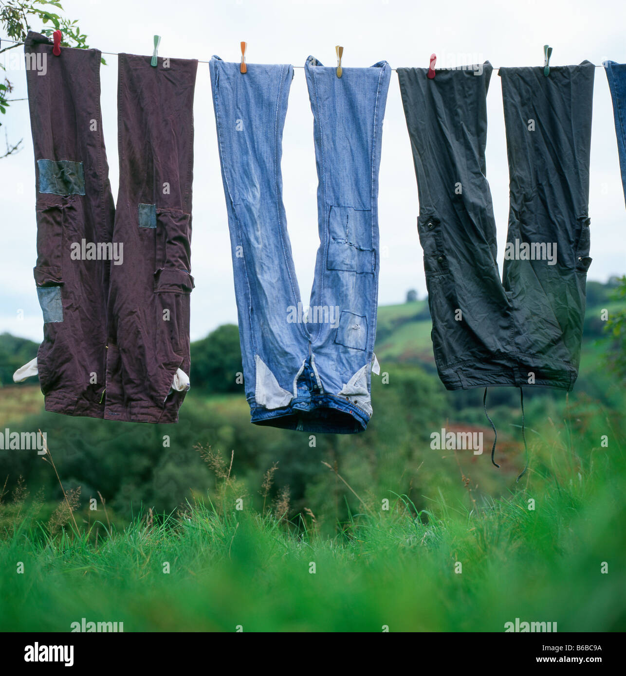 Old patched denim jeans and trousers drying upside down outdoors on a ...
