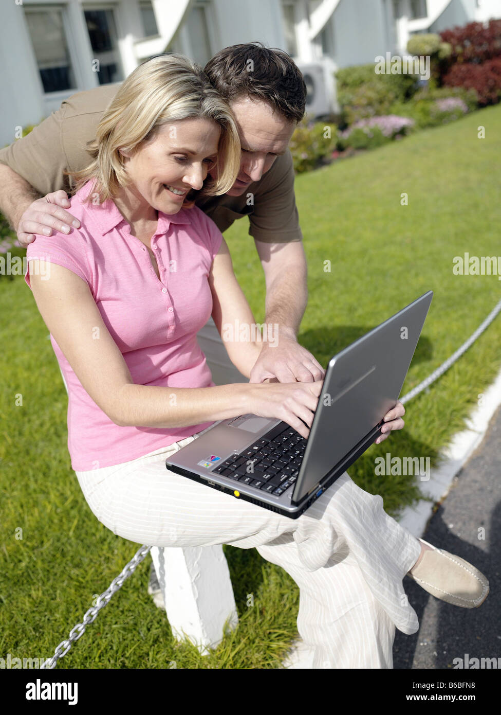 Couple using laptop at front yard Stock Photo - Alamy