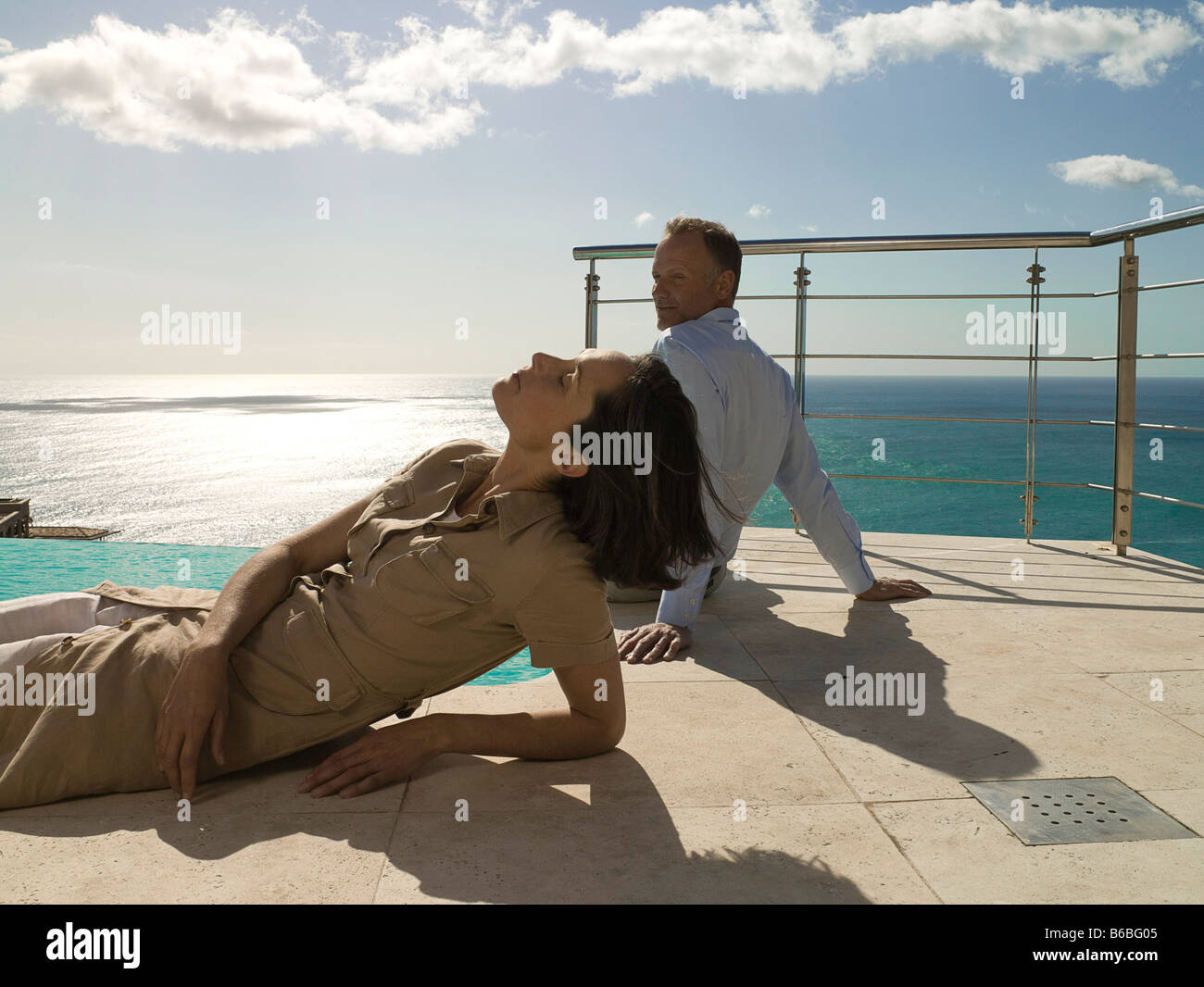 Couple resting at poolside Stock Photo - Alamy
