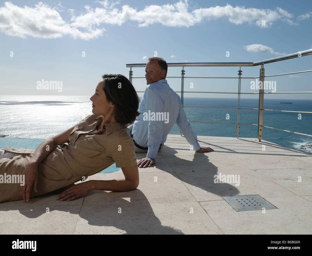 Couple resting at poolside Stock Photo - Alamy