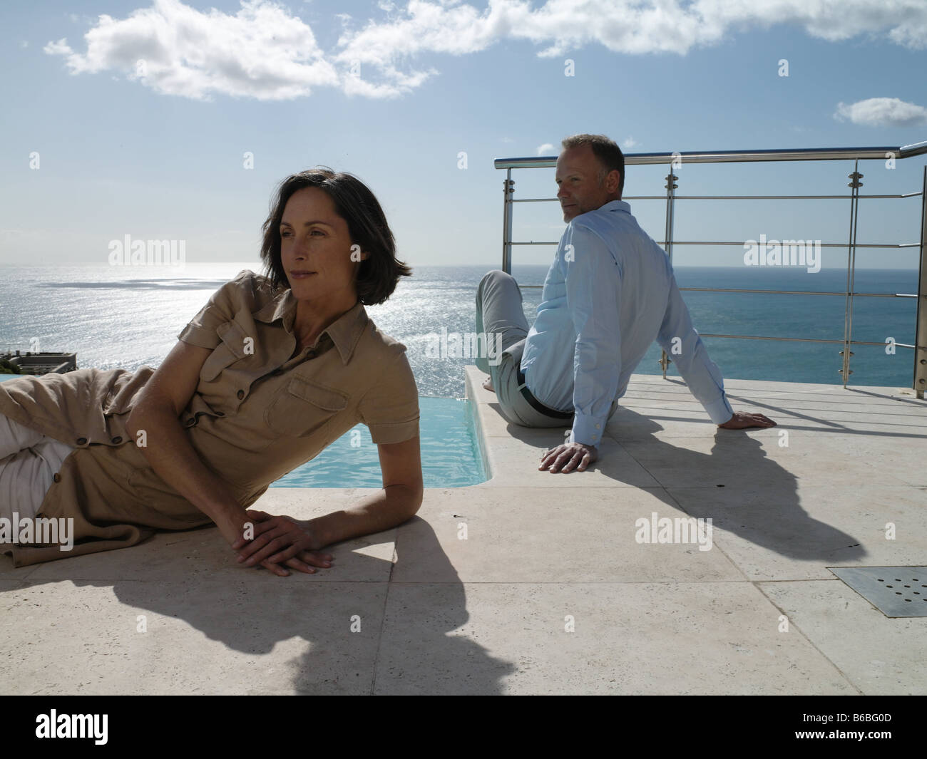 Couple resting at poolside Stock Photo - Alamy