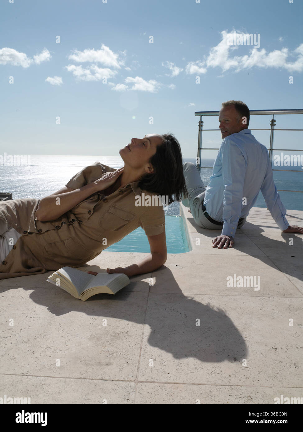 Couple resting at poolside Stock Photo - Alamy