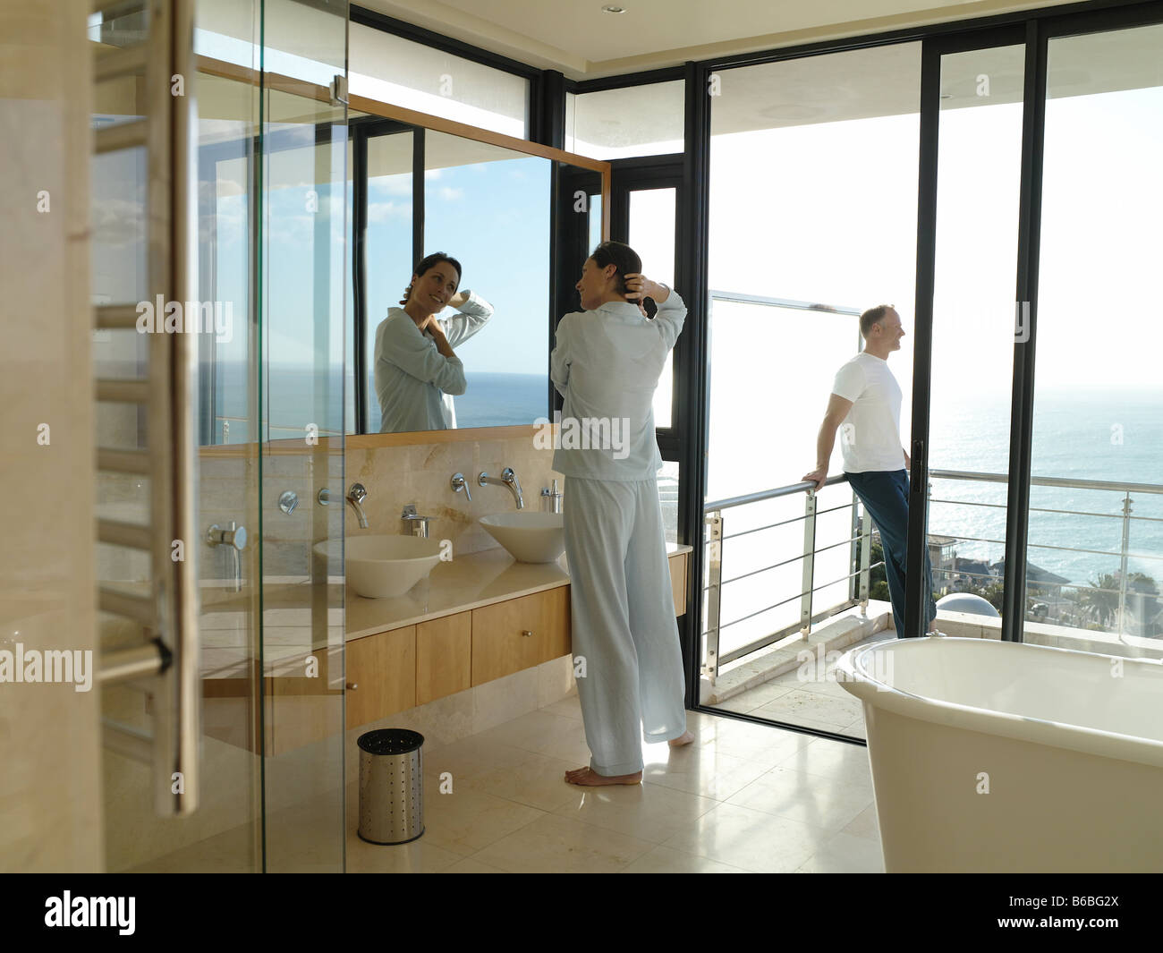 Side profile of woman adjusting her hair at bathroom sink with her ...