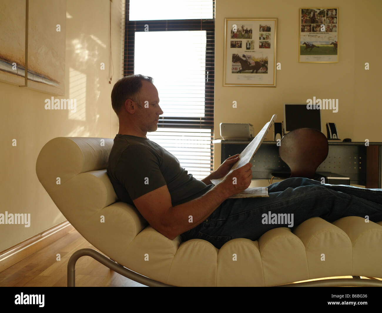 Side profile of man reading newspaper on relaxing chair Stock Photo - Alamy