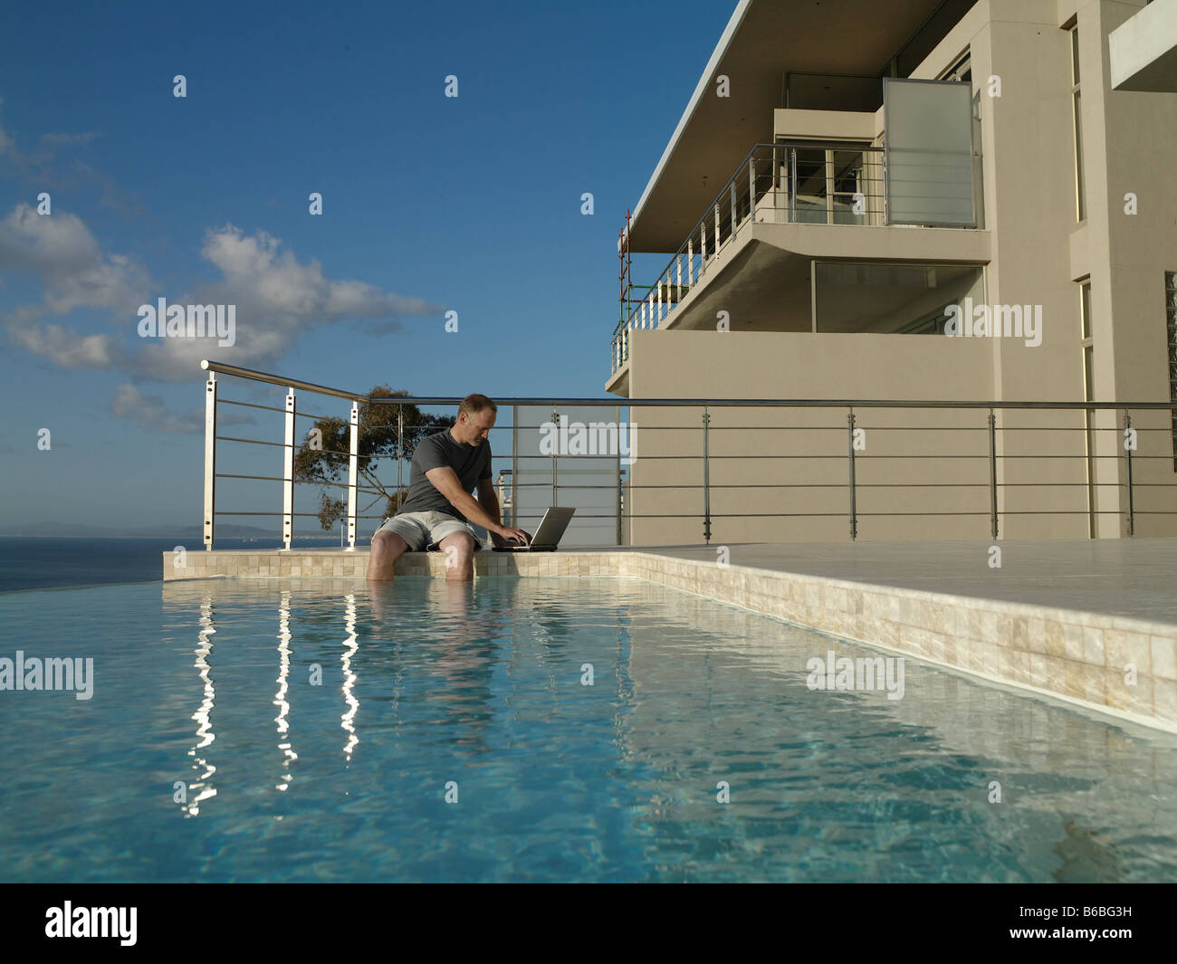 Man working on laptop at poolside Stock Photo - Alamy