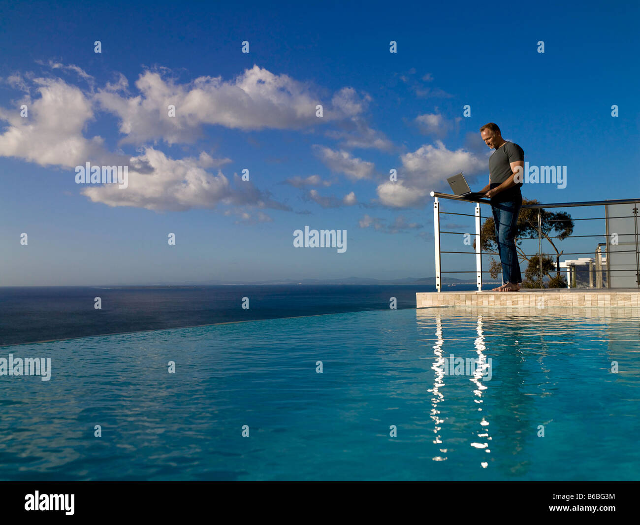 Man working on laptop at poolside Stock Photo - Alamy