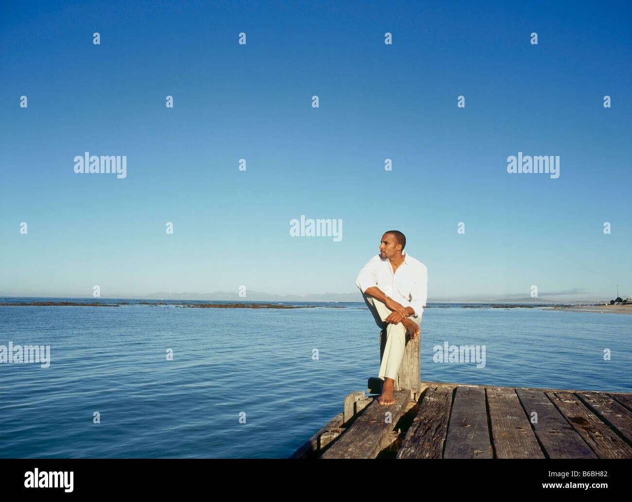 Man sitting on pier Stock Photo - Alamy