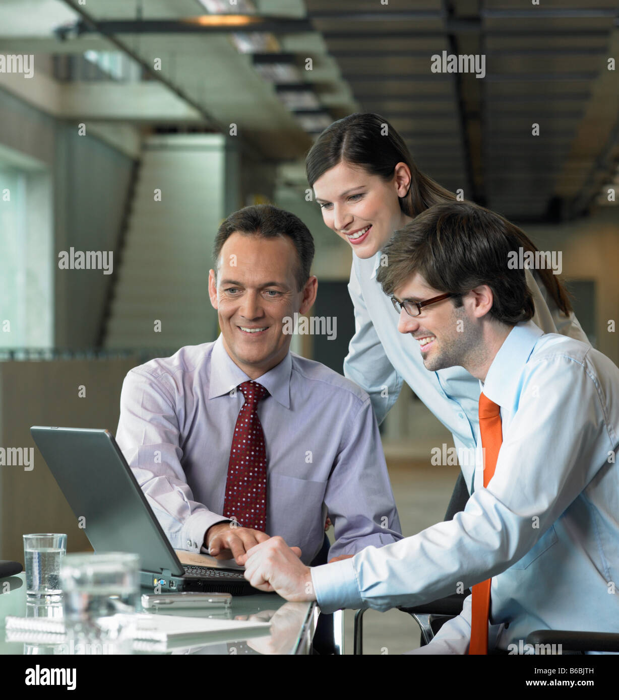 Three businesspeople looking at laptop in office Stock Photo - Alamy