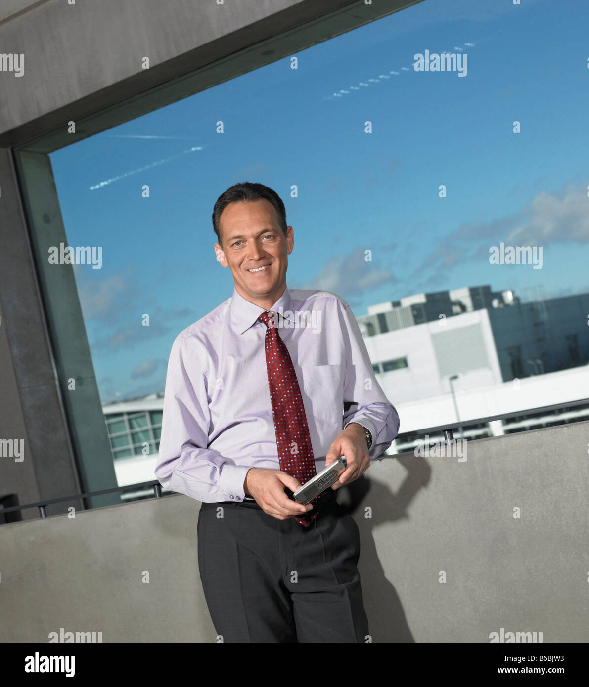Portrait of businessman leaning against wall and smiling Stock Photo ...