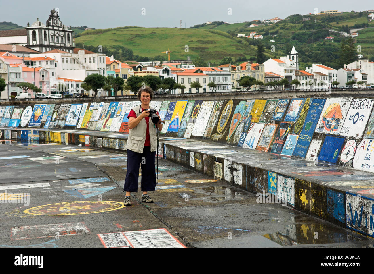 Woman tourist with camera looking at Artwork of sailors done along the ...