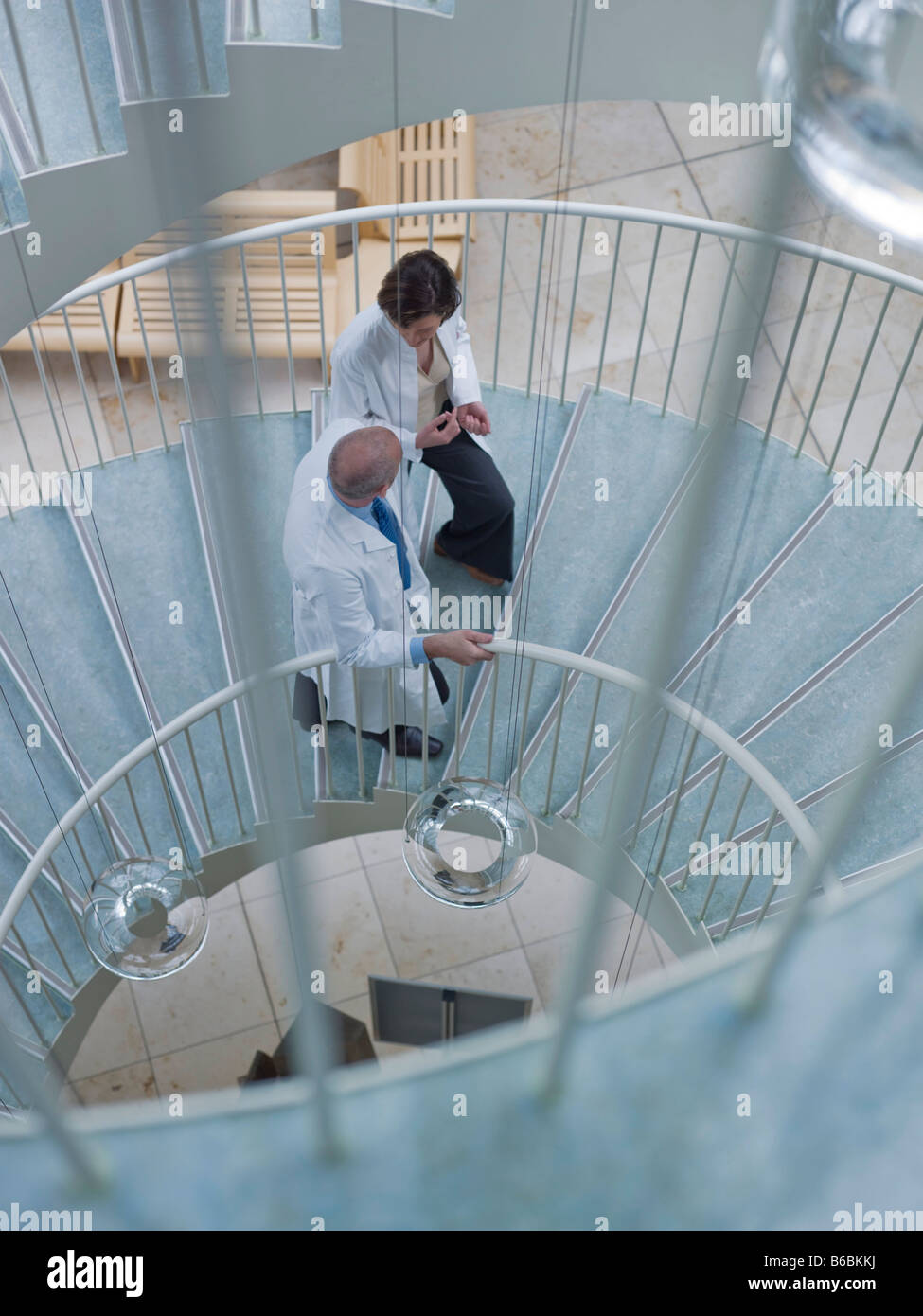 Doctors moving up on spiral staircase Stock Photo - Alamy