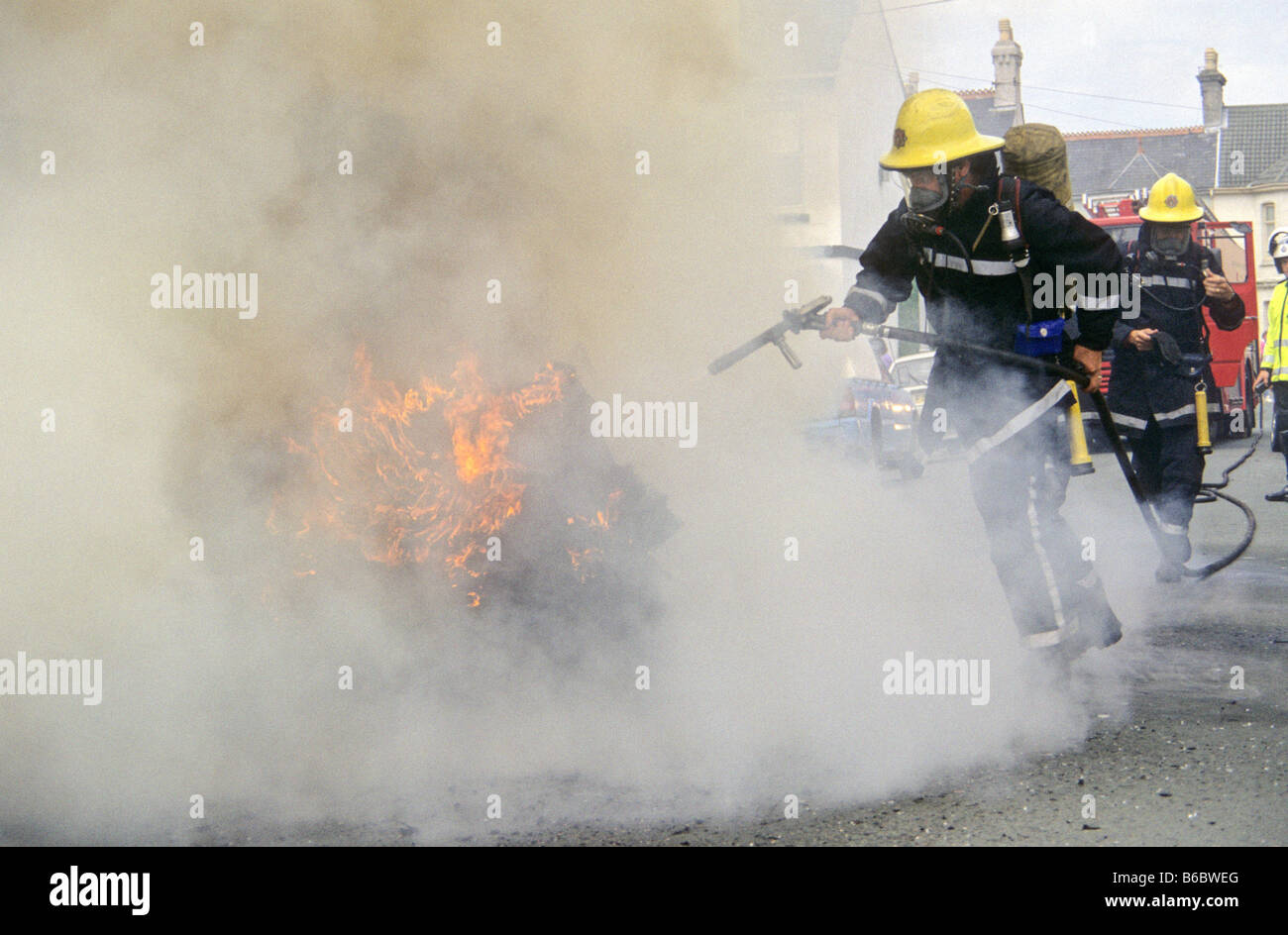 fireman putting out car fire wearing breathing apparatus. flames smoke ...