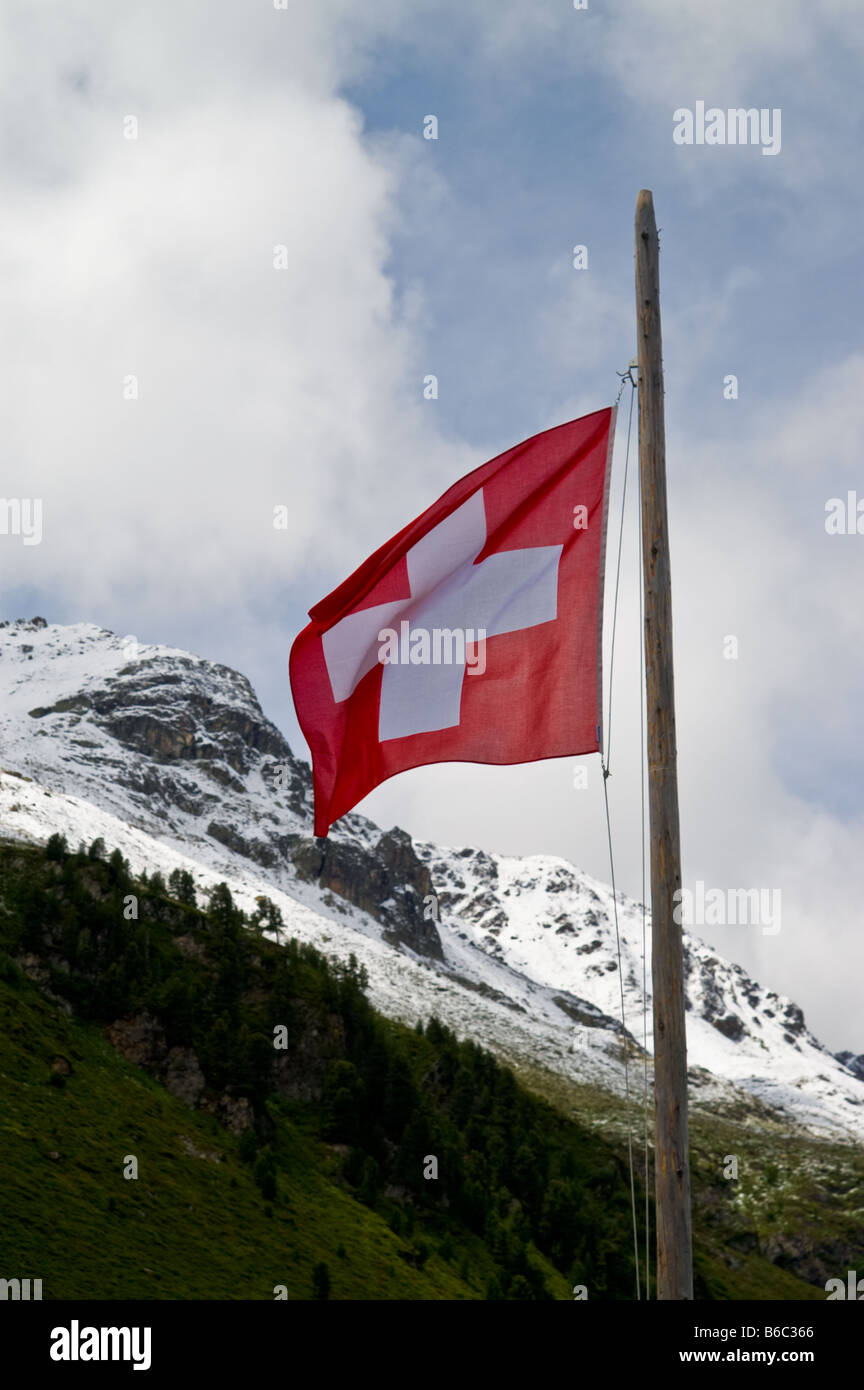 Swiss national flag with snowy peaks in background Stock Photo - Alamy