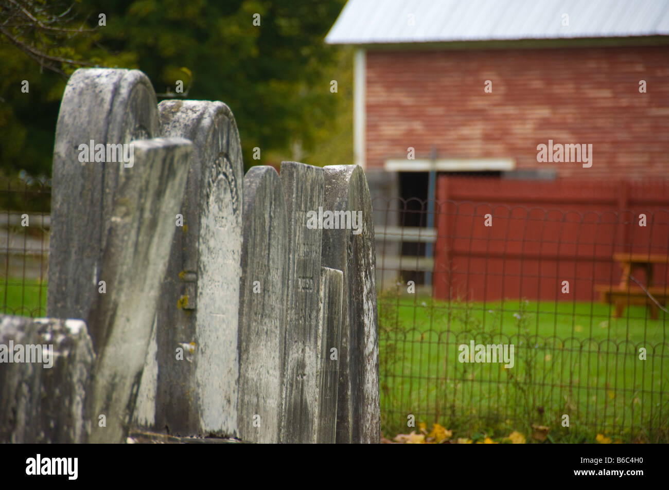 Row of headstones in an old graveyard A barn is in the background Stock ...