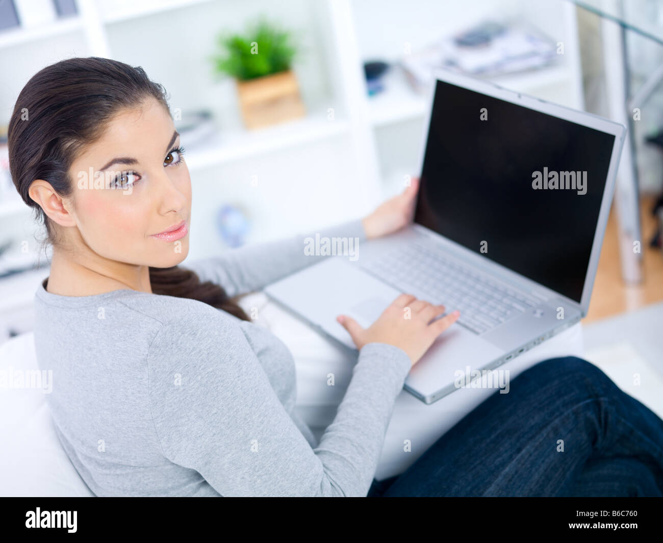 Young woman sitting on couch and working on laptop Stock Photo - Alamy