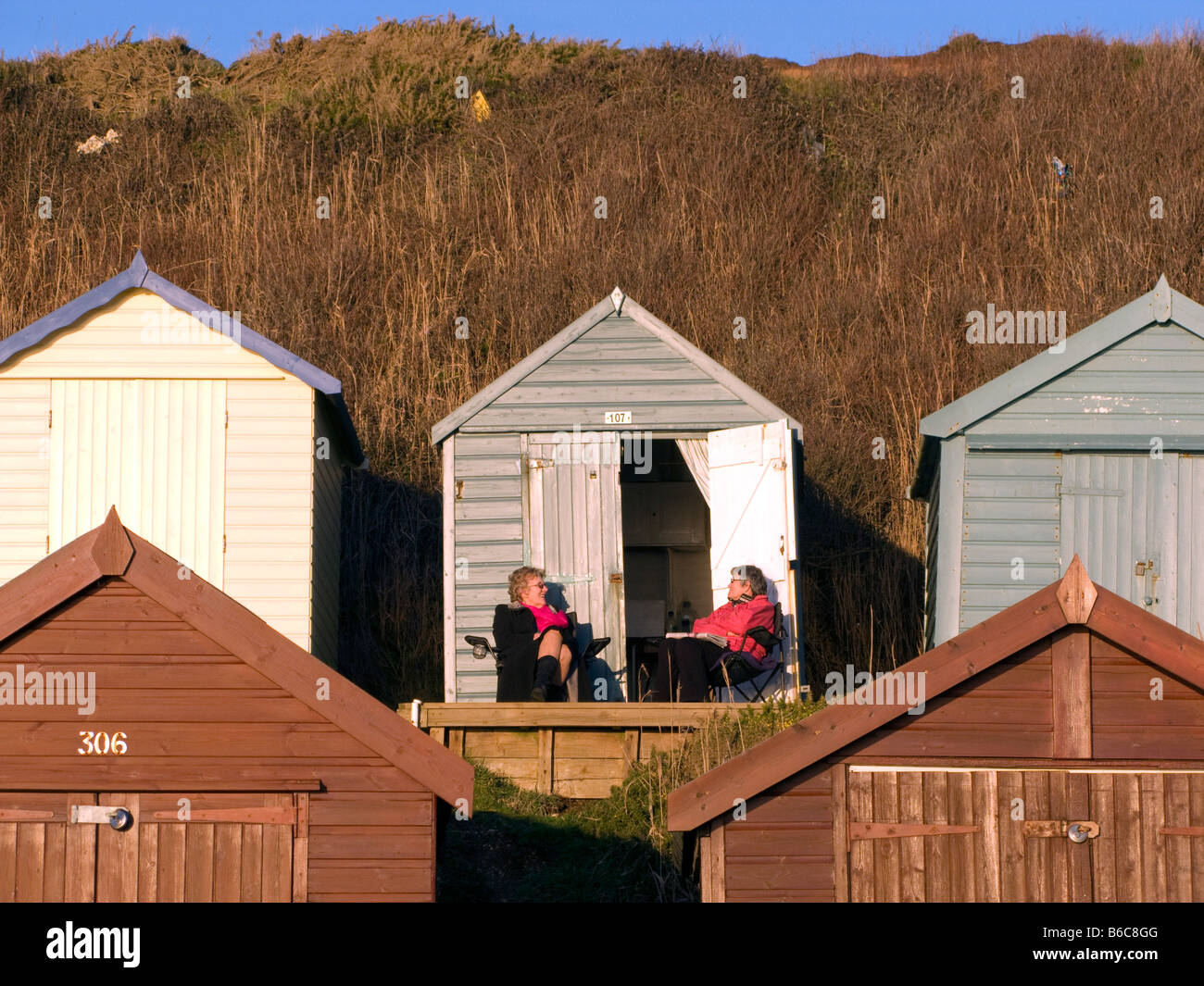 Two Women Sitting Outside Beach Hut In Winter's Afternoon Sunlight ...