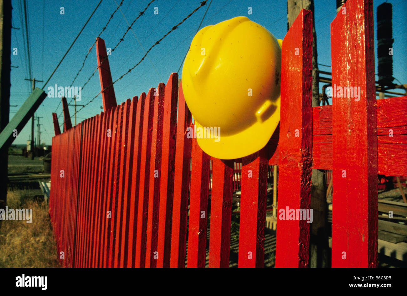 Red fence with a yellow construction hat Stock Photo - Alamy