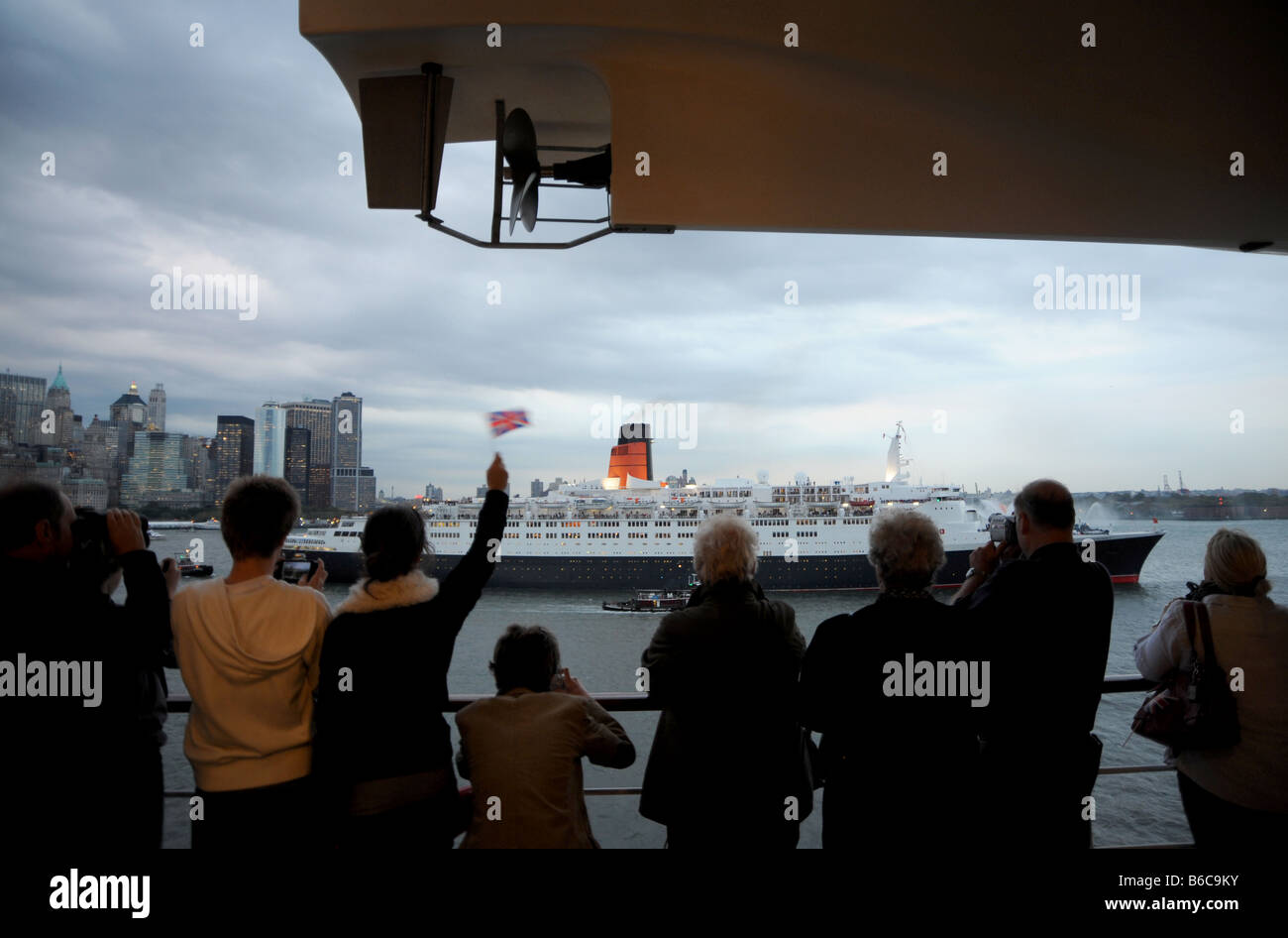 Passengers wave to the QE2 as she leaves New York for the last time ...