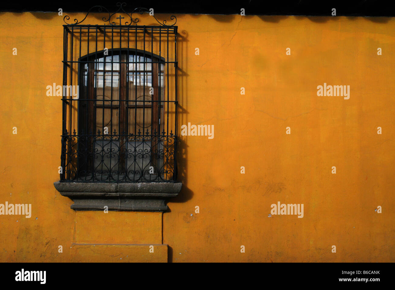 Barred window set in an orange wall Stock Photo - Alamy