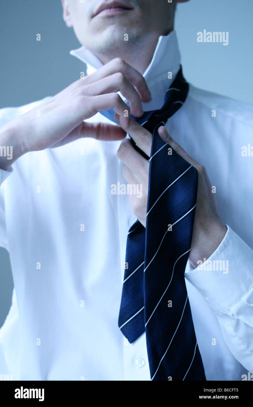Close-up of businessman tying his tie Stock Photo - Alamy