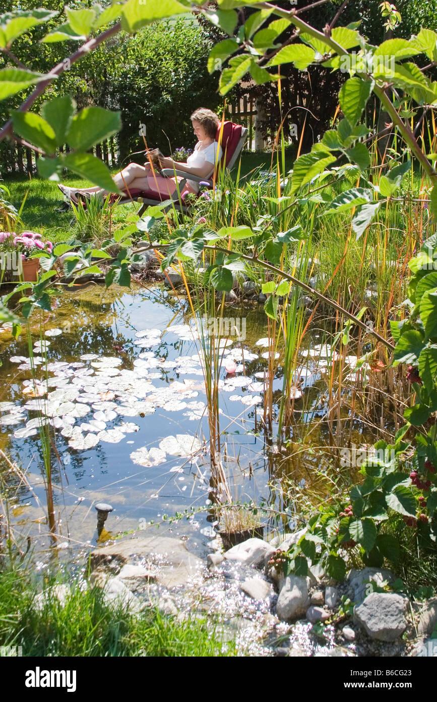 Side profile of woman reading magazine on lounge chair in lawn Stock ...