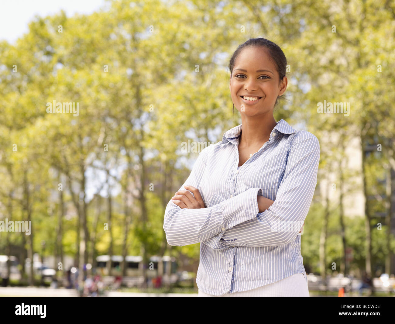 Mixed race woman with arms crossed in park Stock Photo - Alamy