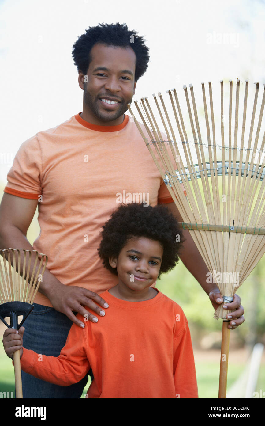 African father and son holding rakes Stock Photo - Alamy