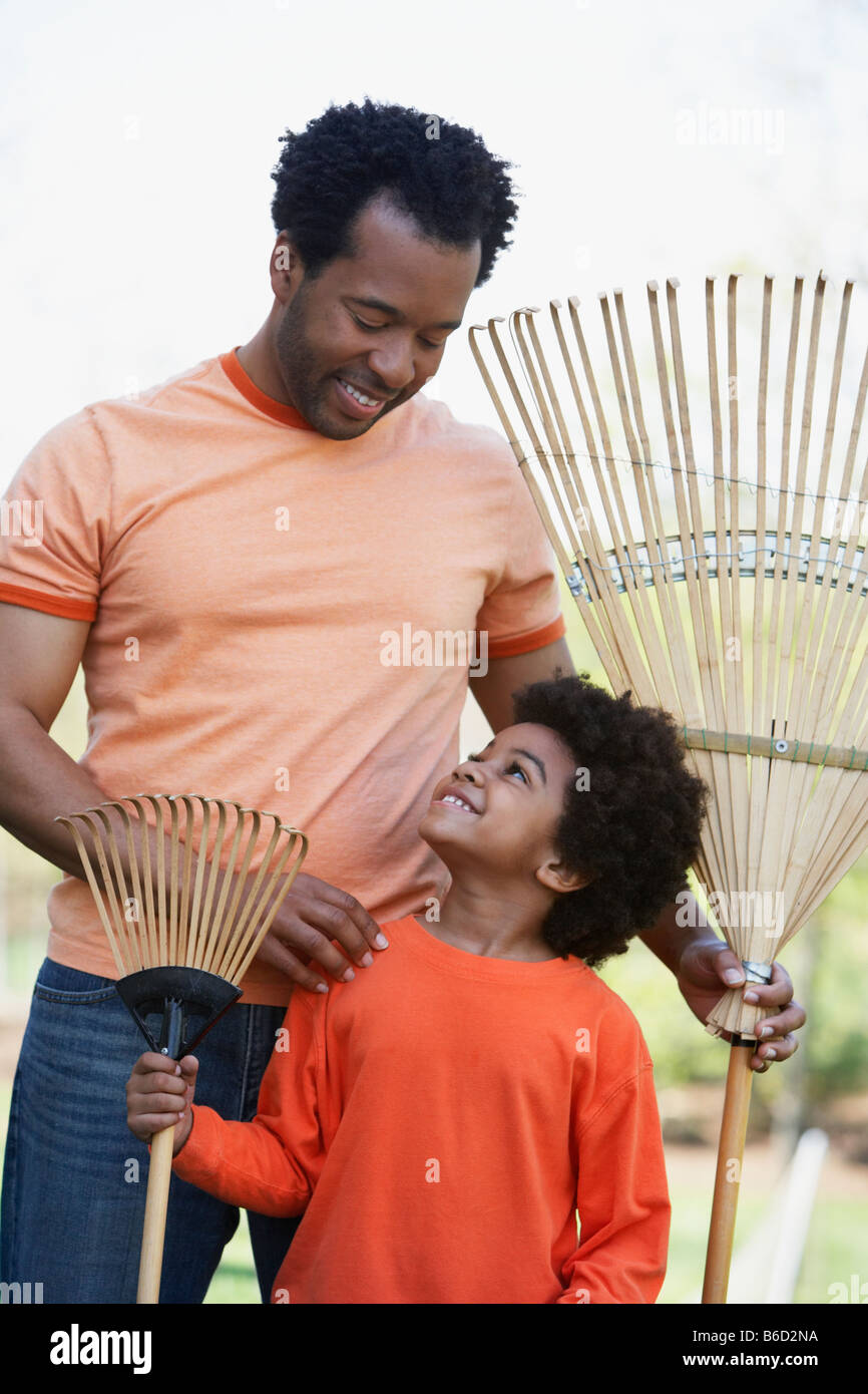 African father and son holding rakes Stock Photo - Alamy