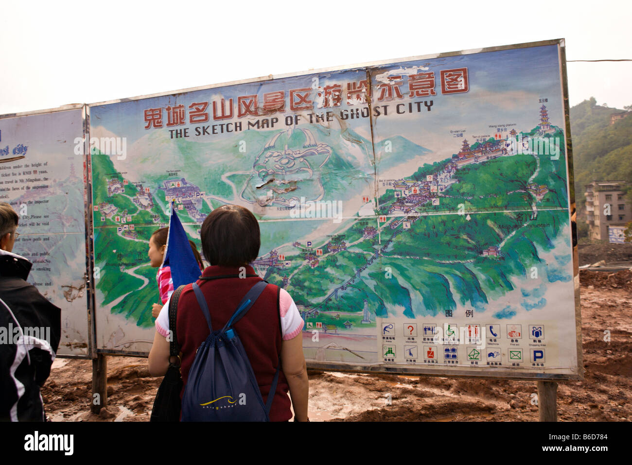 CHINA FENGDU Tour guide with flag stands in the mud in front of a ...