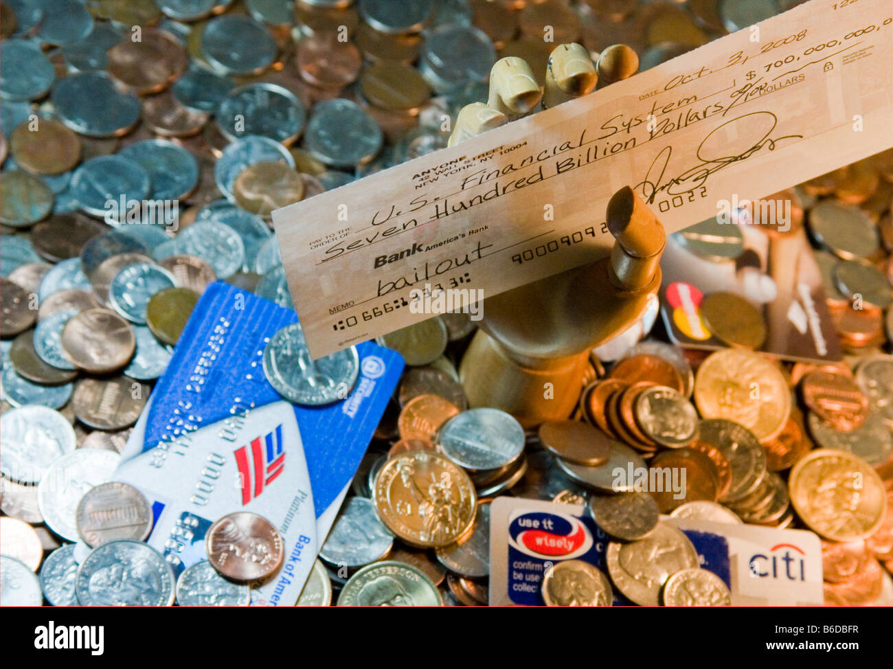 A wooden mechanical hand emerges from a sea of US coins holding a check ...