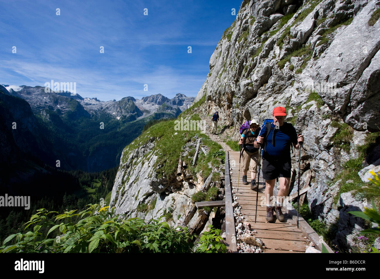 Group of hikers on bridge crossing steep cliff near Koenigssee ...