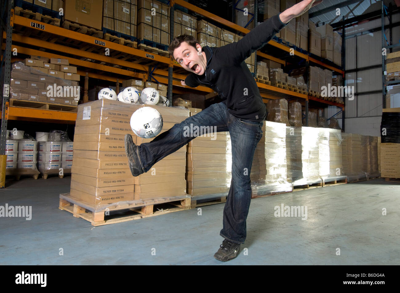 A man in a warehouse kicking one of the Fairtrade footballs he has ...