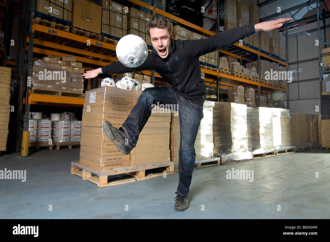 A man in a warehouse kicking one of the Fairtrade footballs he has ...