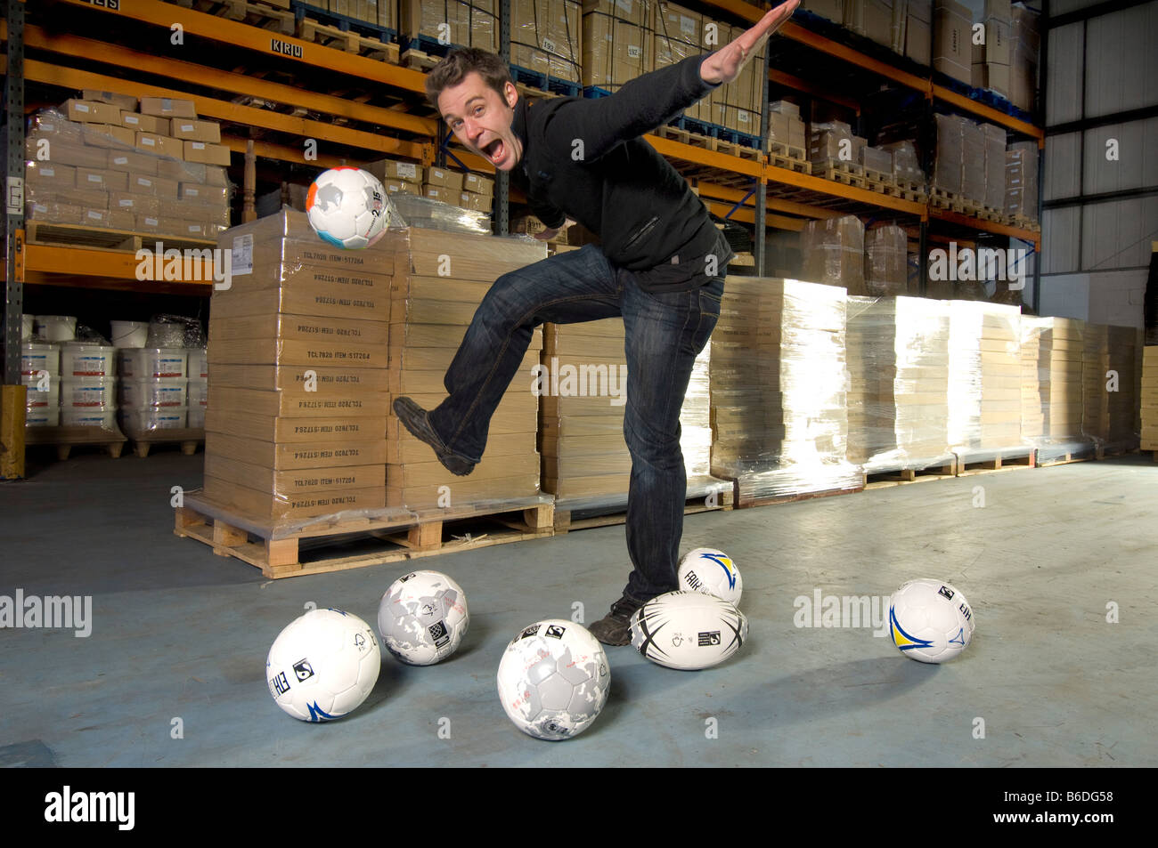 A man in a warehouse kicking one of the Fairtrade footballs he has ...