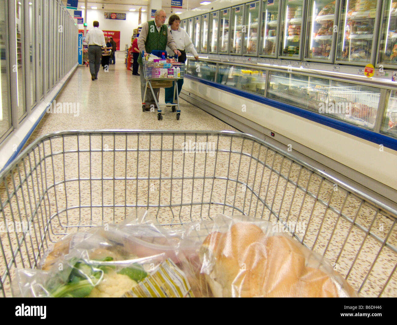 A supermarket trolley with produce in an isle Stock Photo - Alamy