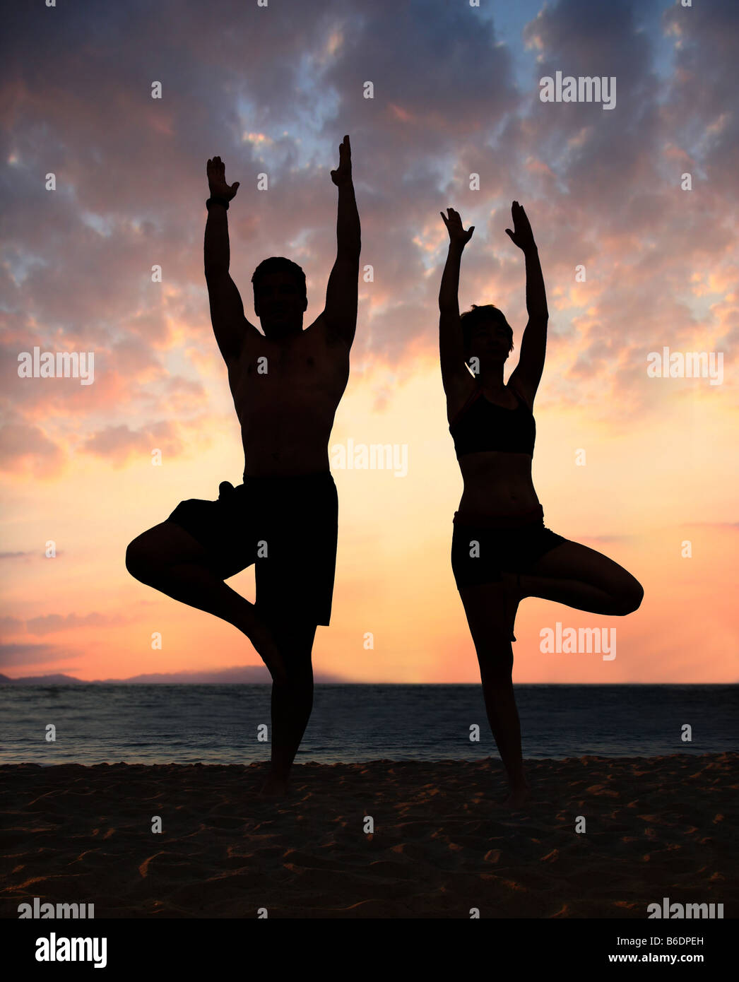 Couple doing yoga exercise on the beach Stock Photo - Alamy