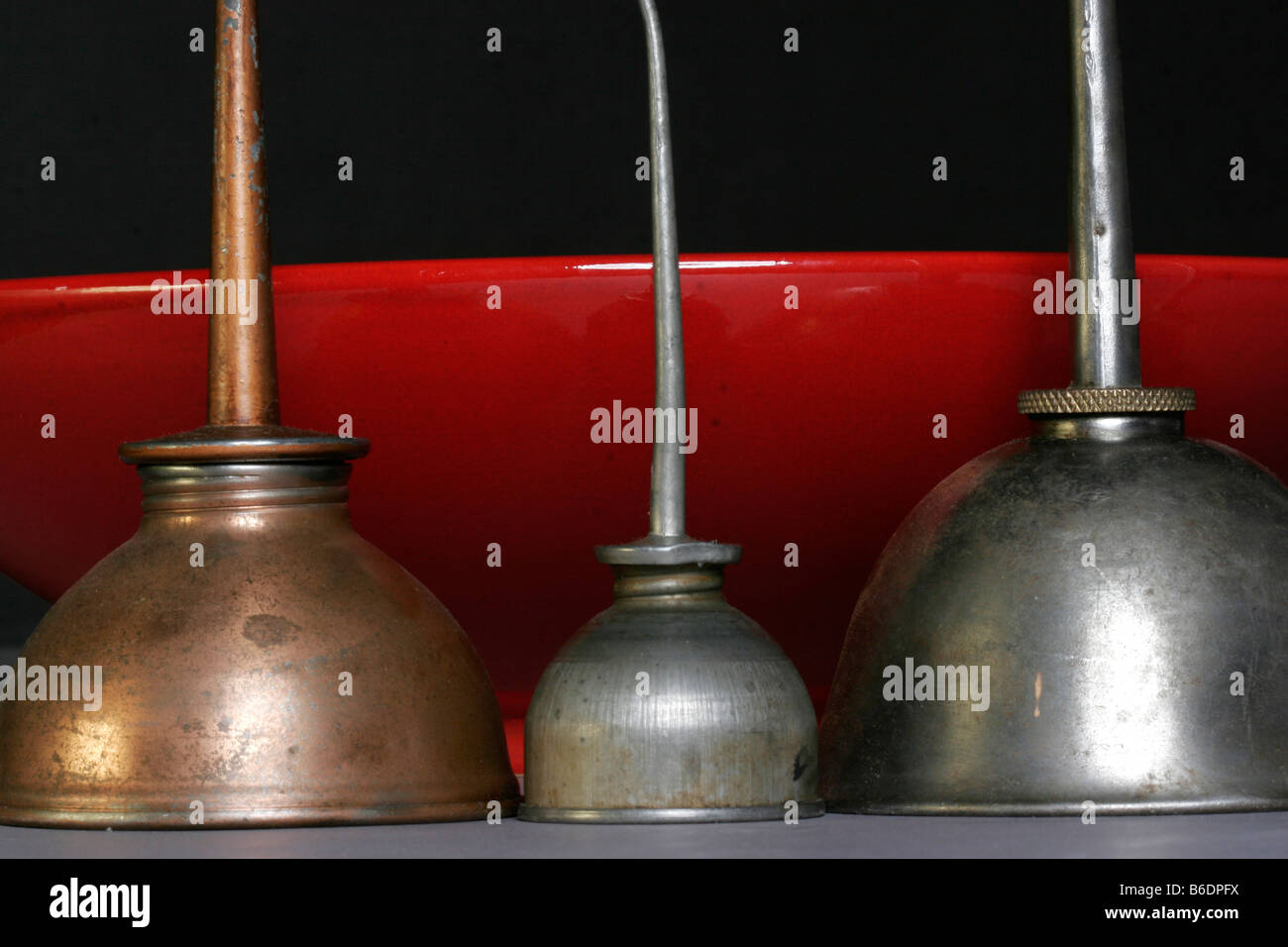 three oil cans in front of a red ceramic bowl and black background ...