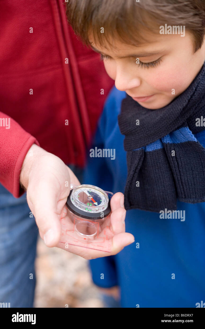 Reading a compass. Boy reading a compass being held in his father's ...