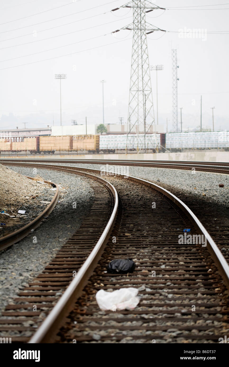 Looking down a curved train track with garbage on the track and a train ...