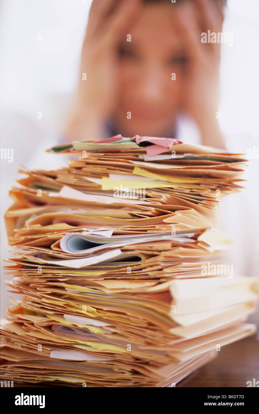 Overworked doctor sitting behind a pile of patients notes Stock Photo ...